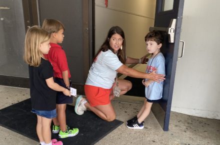 Child Holding Door Open At School